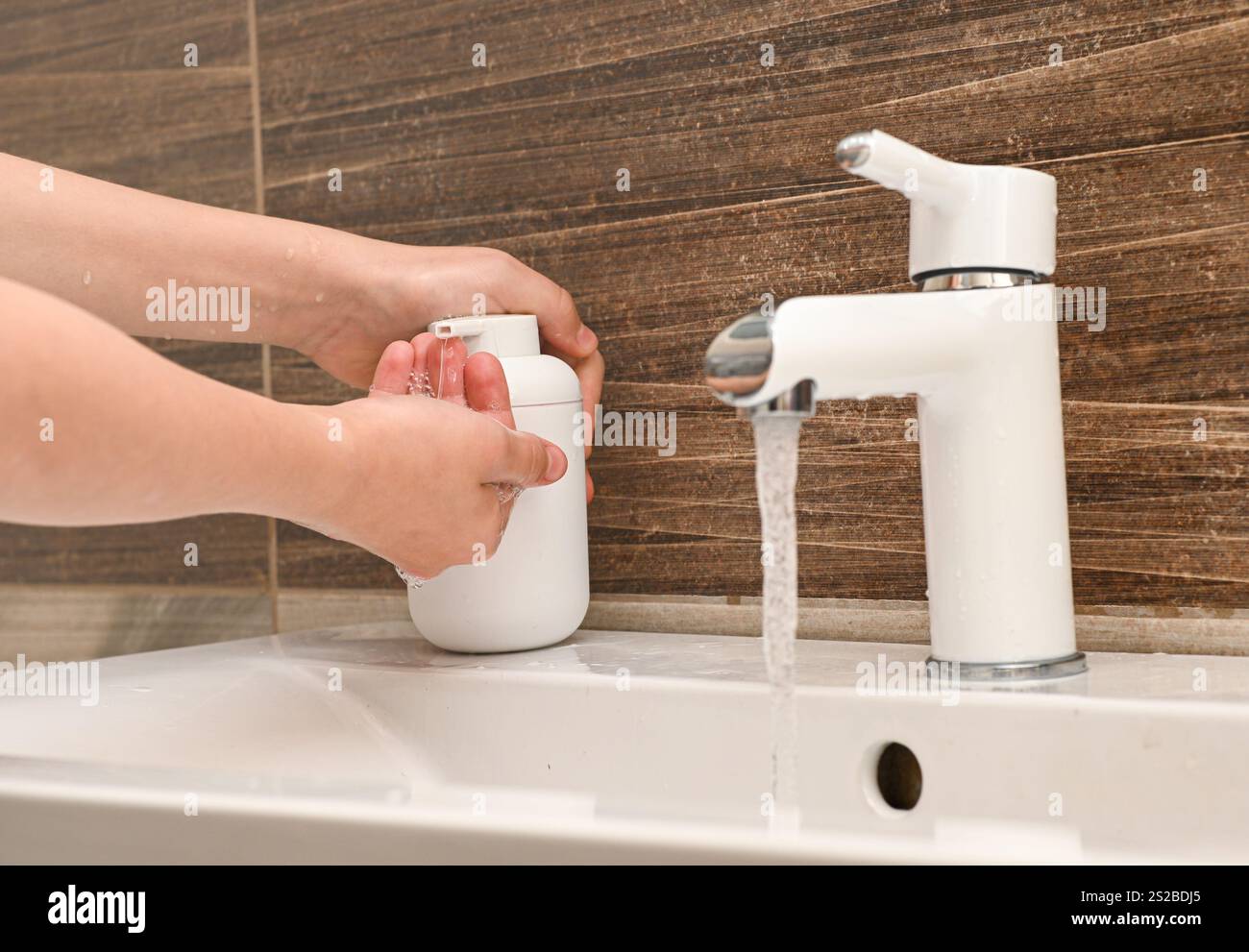 Kid using liquid soap and running water for hand washing and hygiene ...