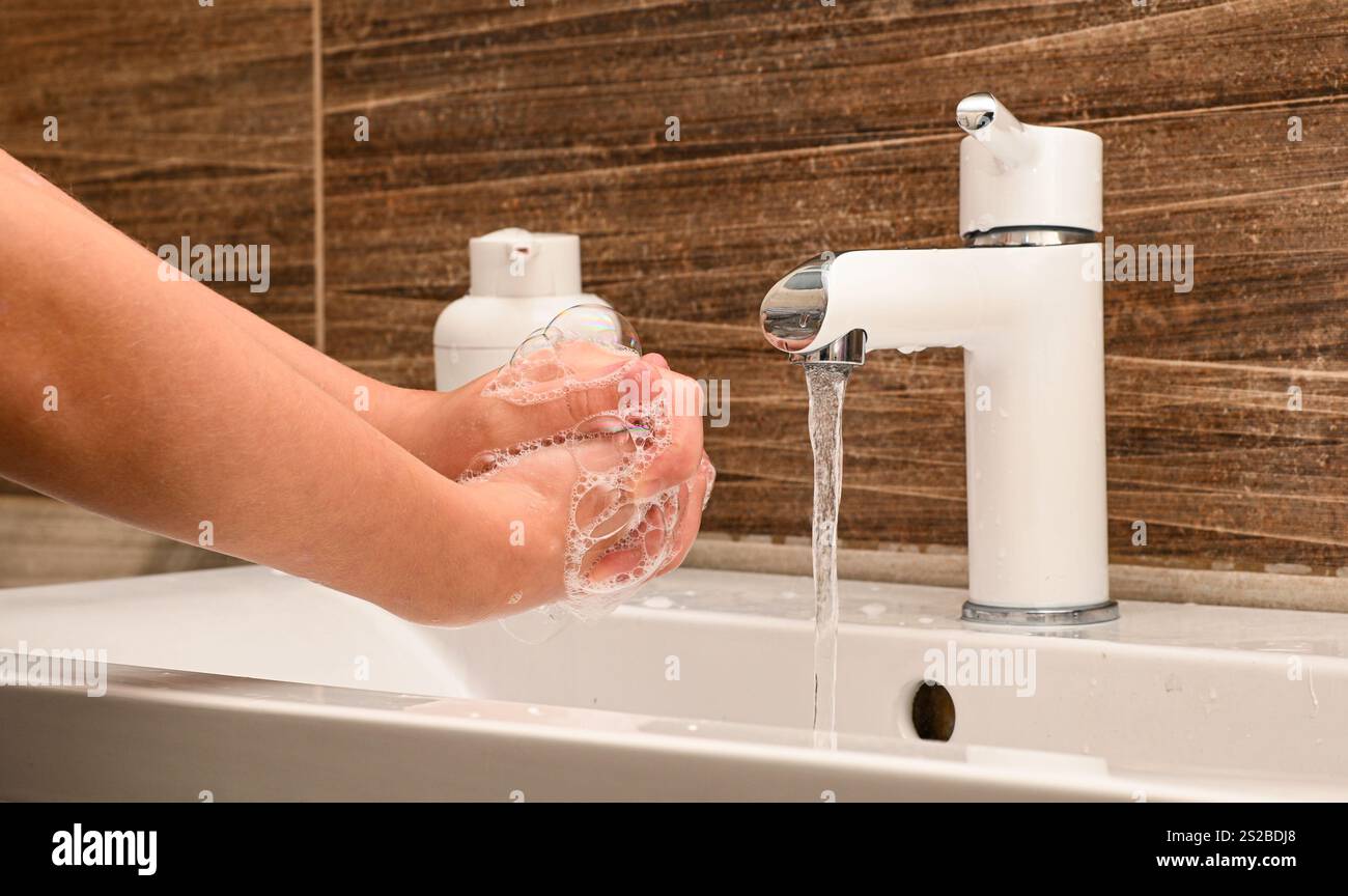 Kid using liquid soap and running water for hand washing and hygiene ...