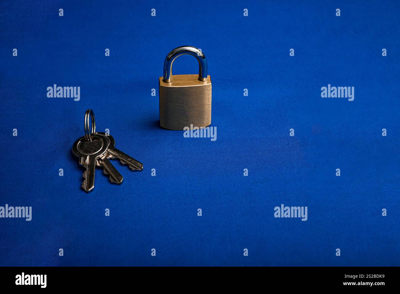 Metal padlock and keys lying on a vibrant blue backdrop, symbolizing ...