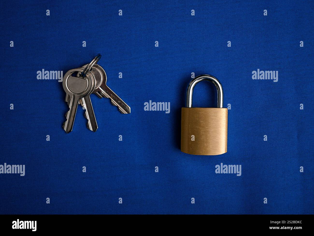 Metal padlock and keys lying on a vibrant blue backdrop, symbolizing ...