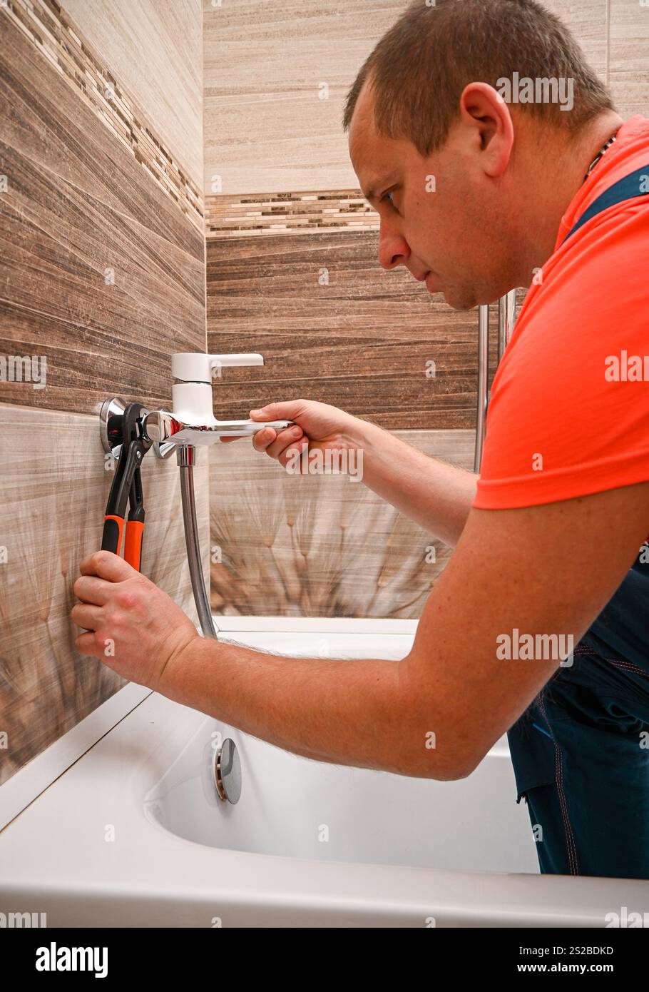 Professional plumber working on installing or repairing faucet in ...