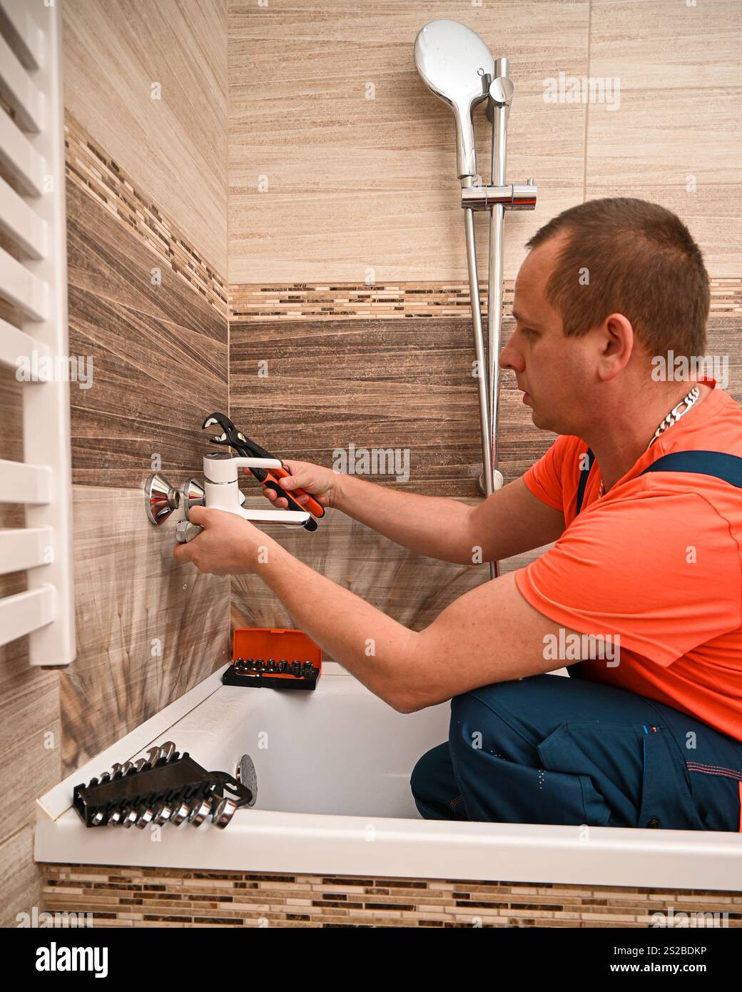 Professional plumber working on installing or repairing faucet in ...