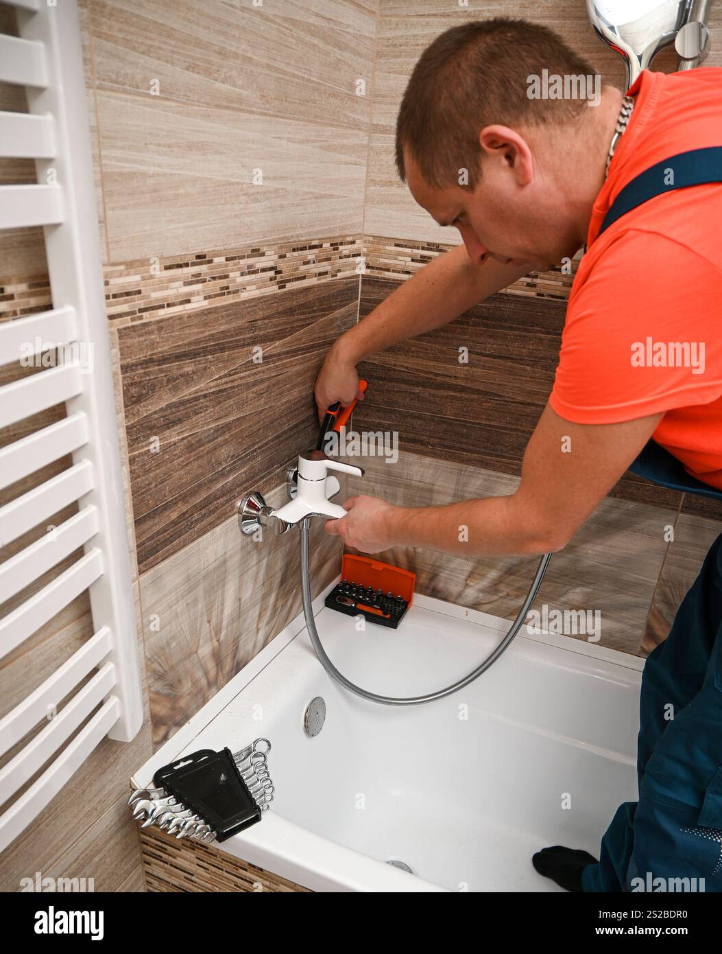 Professional plumber working on installing or repairing faucet in ...