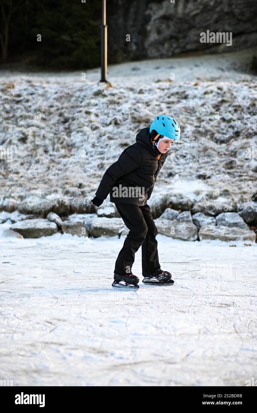 Child enjoying winter activity, ice skating on a frozen lake, wearing a ...