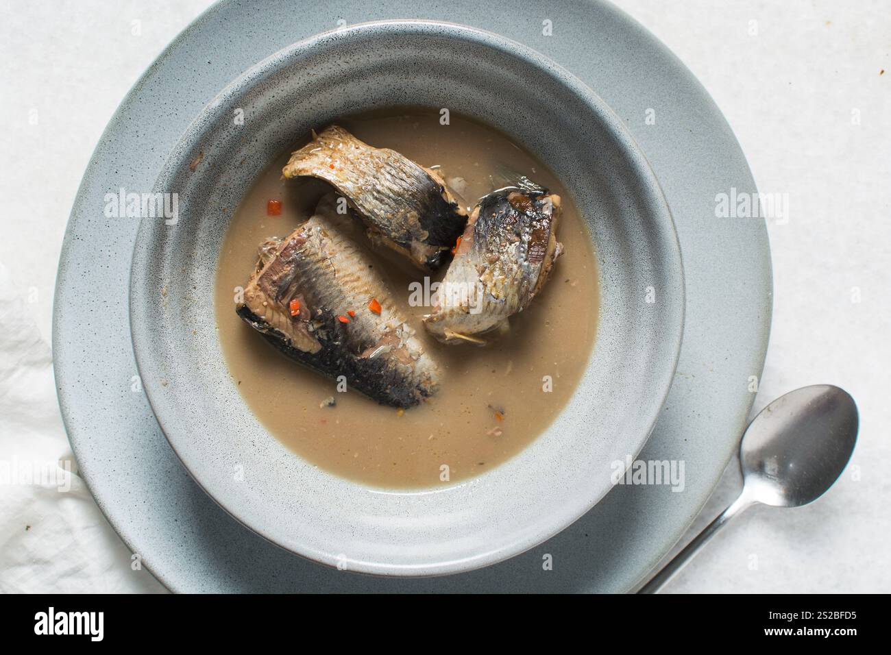 Overhead view of Nigerian pepper soup with fish in a grey soup plate ...