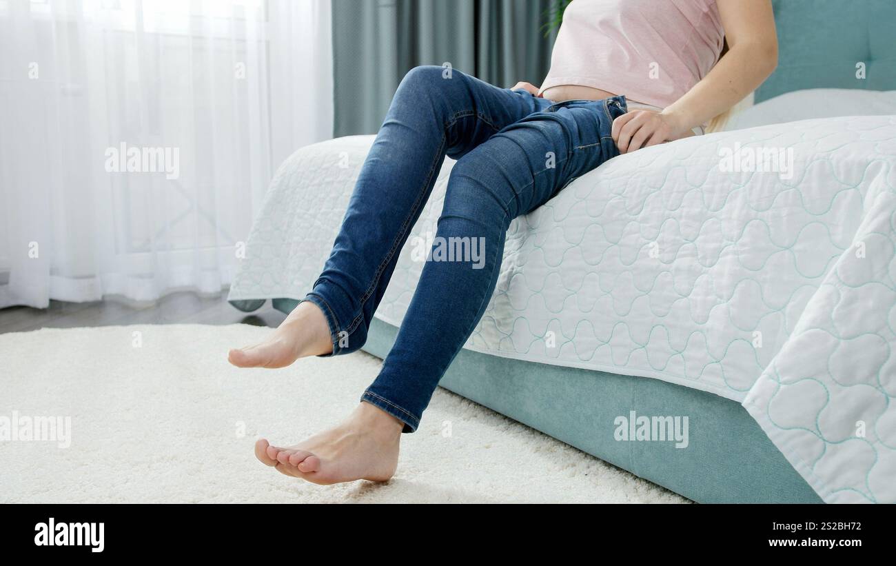 Young woman with wide hips and obese thighs sitting on bed and putting ...