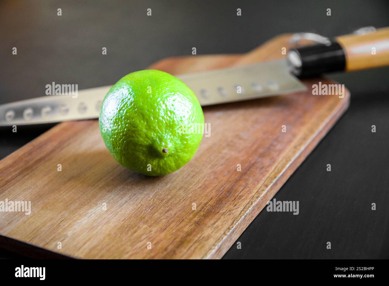 Lime and traditional Japanese gyuto chief knife on a cutting board ...