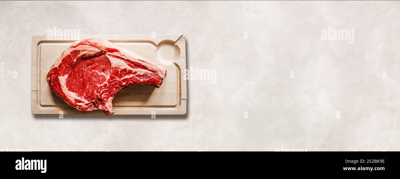 Raw beef prime rib and wooden cutting board isolated on white concrete ...