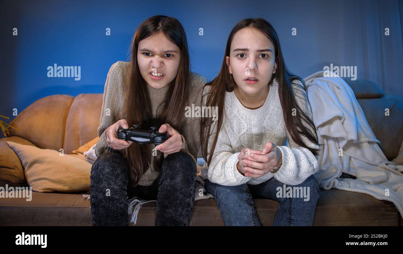 Two concentrated girls playing video games on game console in living ...