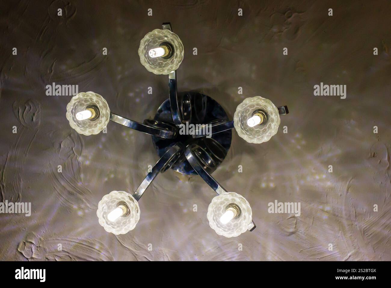 Modern ceiling light fixture with six illuminated bulbs seen from ...