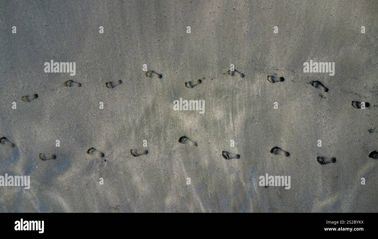 Footprints in black sand seen from above Stock Photo - Alamy