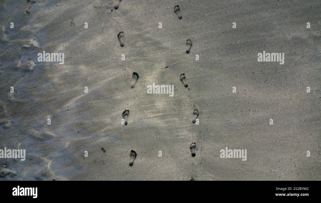 Footprints in black sand seen from above Stock Photo - Alamy