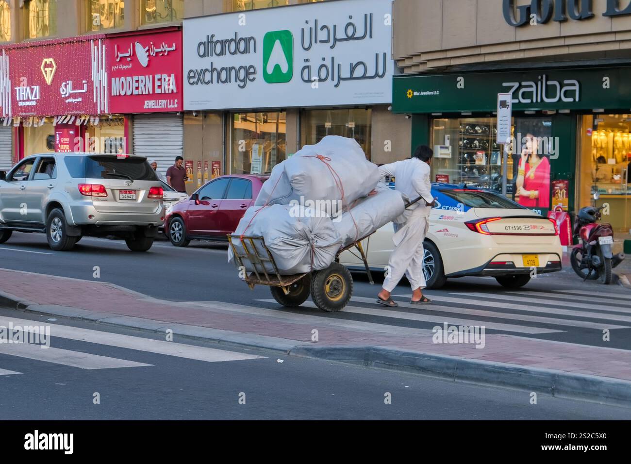 Dubai, UAE, Jan.5: Middle eastern worker pushing overloaded wheelbarrow ...