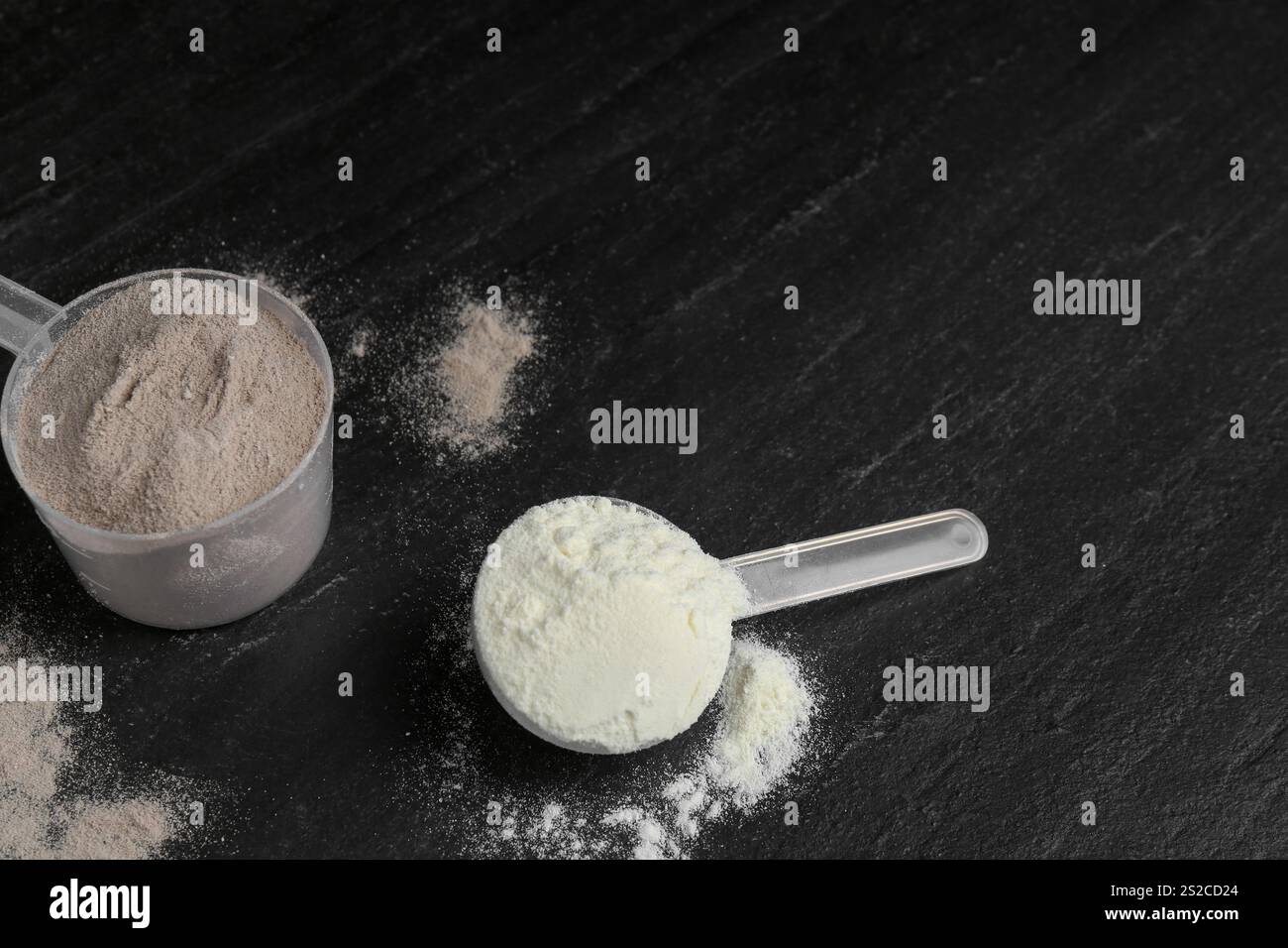 Protein powders in scoops on dark textured table, space for text Stock ...