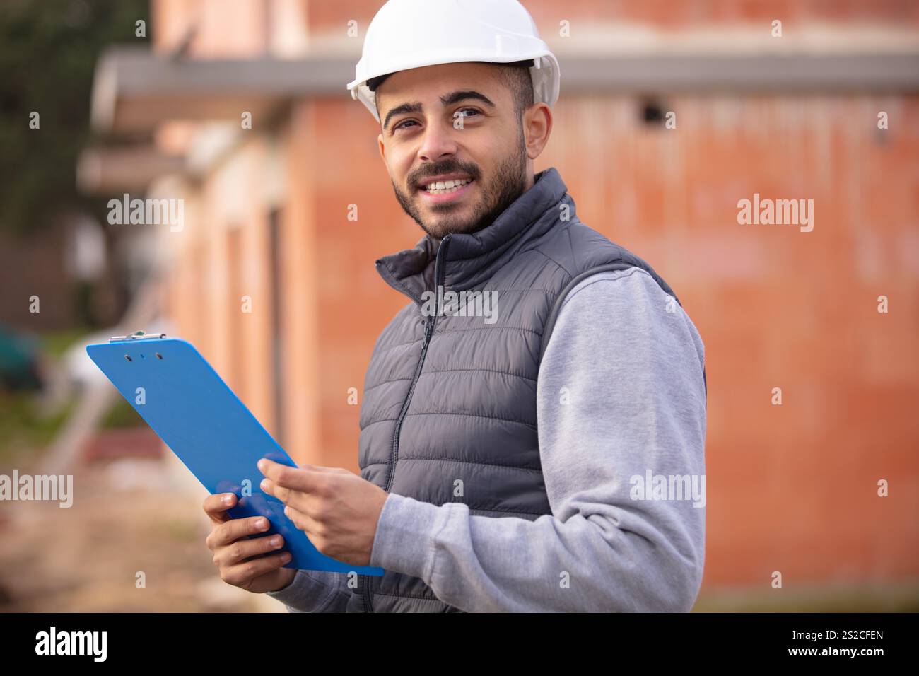male construction inspector checking outdoor building holding list ...