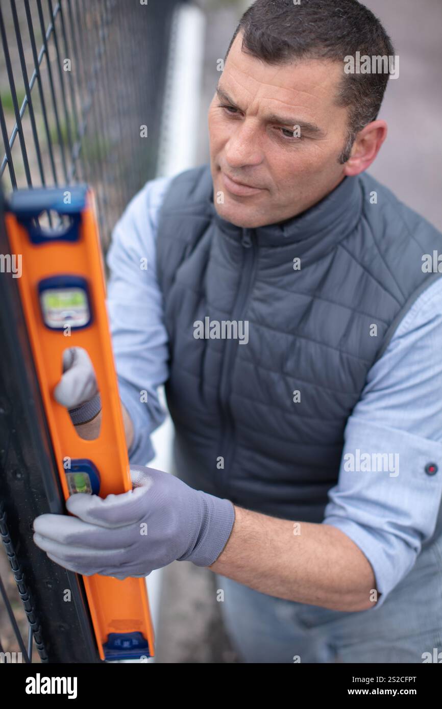 worker installing metal fence and checking with spirit level Stock ...