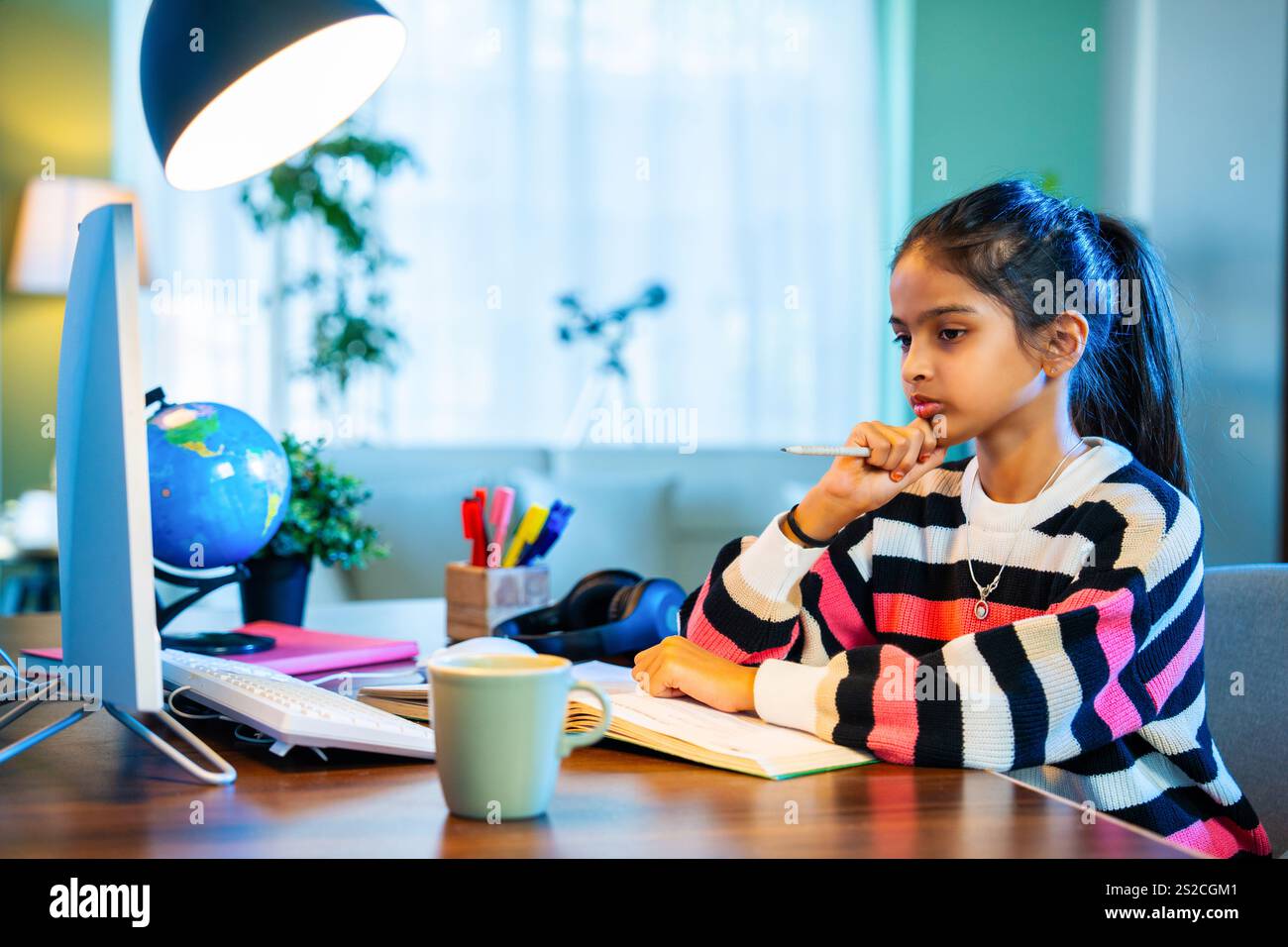 Studious Indian Asian Elementary Grade Girl Attending Virtual Online Class at Home Using ...