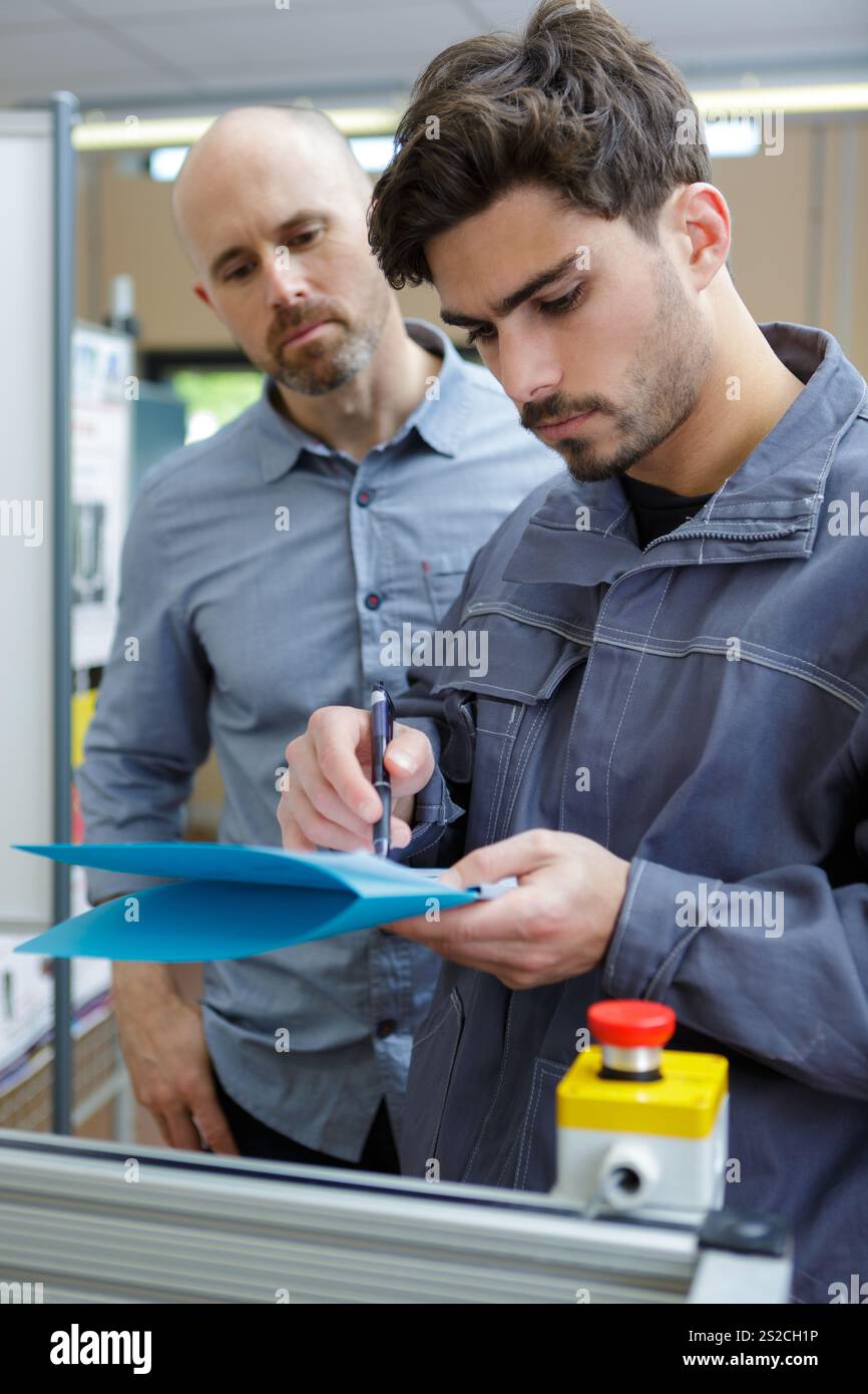 two manual workers checking notes Stock Photo - Alamy