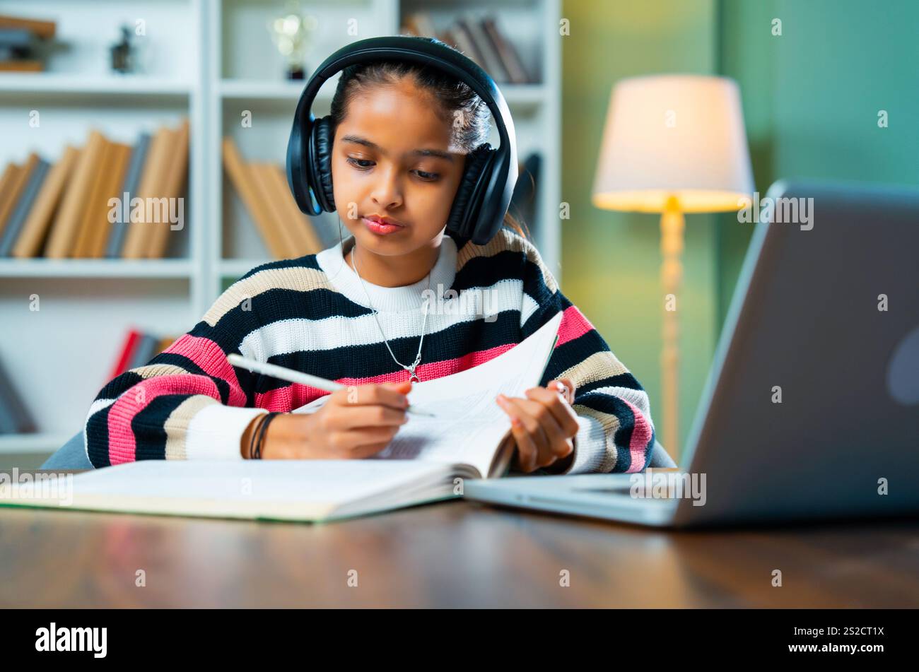 Studious Indian Asian Elementary Grade Girl Attending Virtual Online Class at Home Using ...