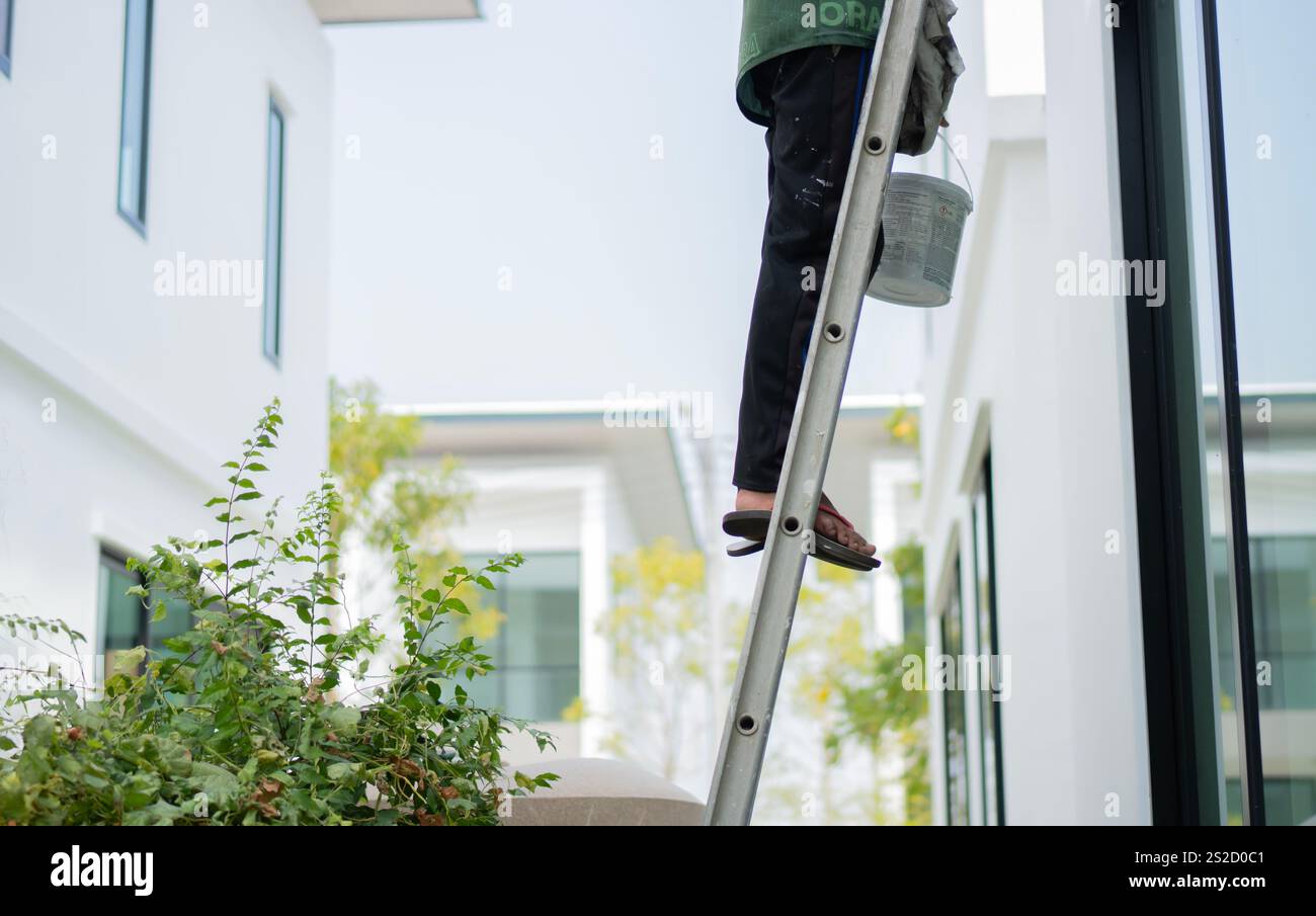 Cropped shot of painter man at work with a roller, bucket and ladder ...