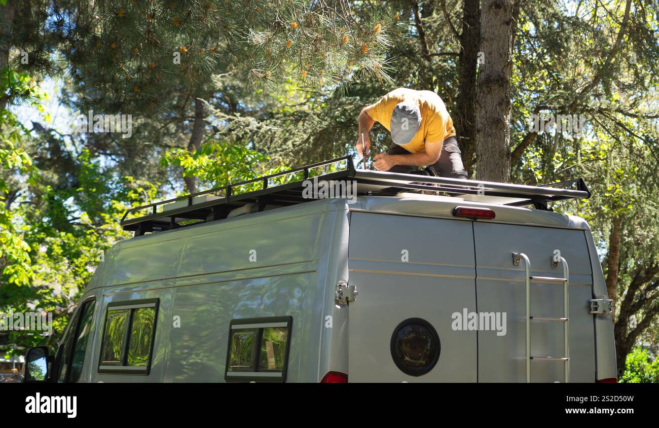 Skilled technician installing a roof rack on a camper van in a forest ...
