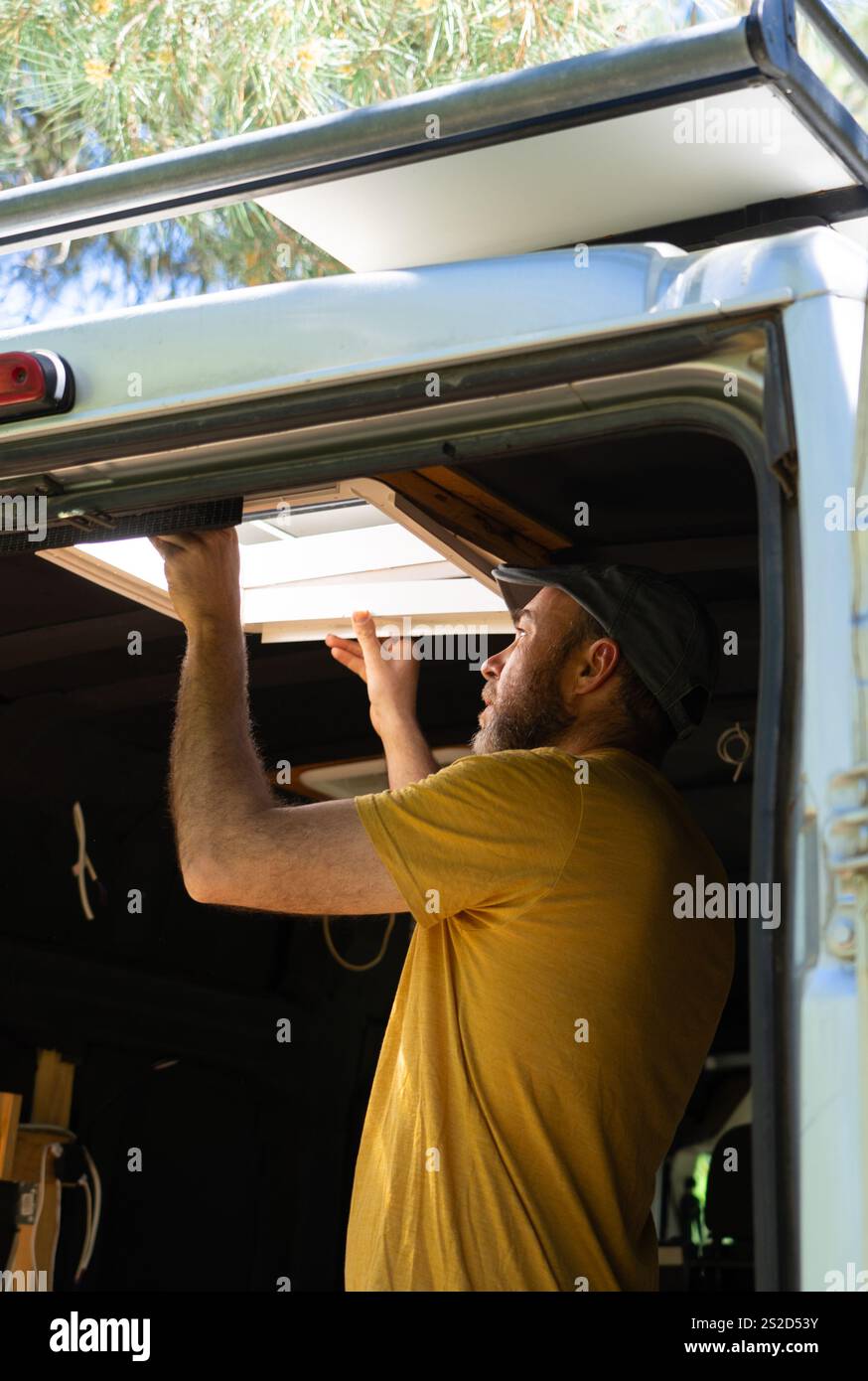 Camper van owner installing a new roof vent for better air circulation ...