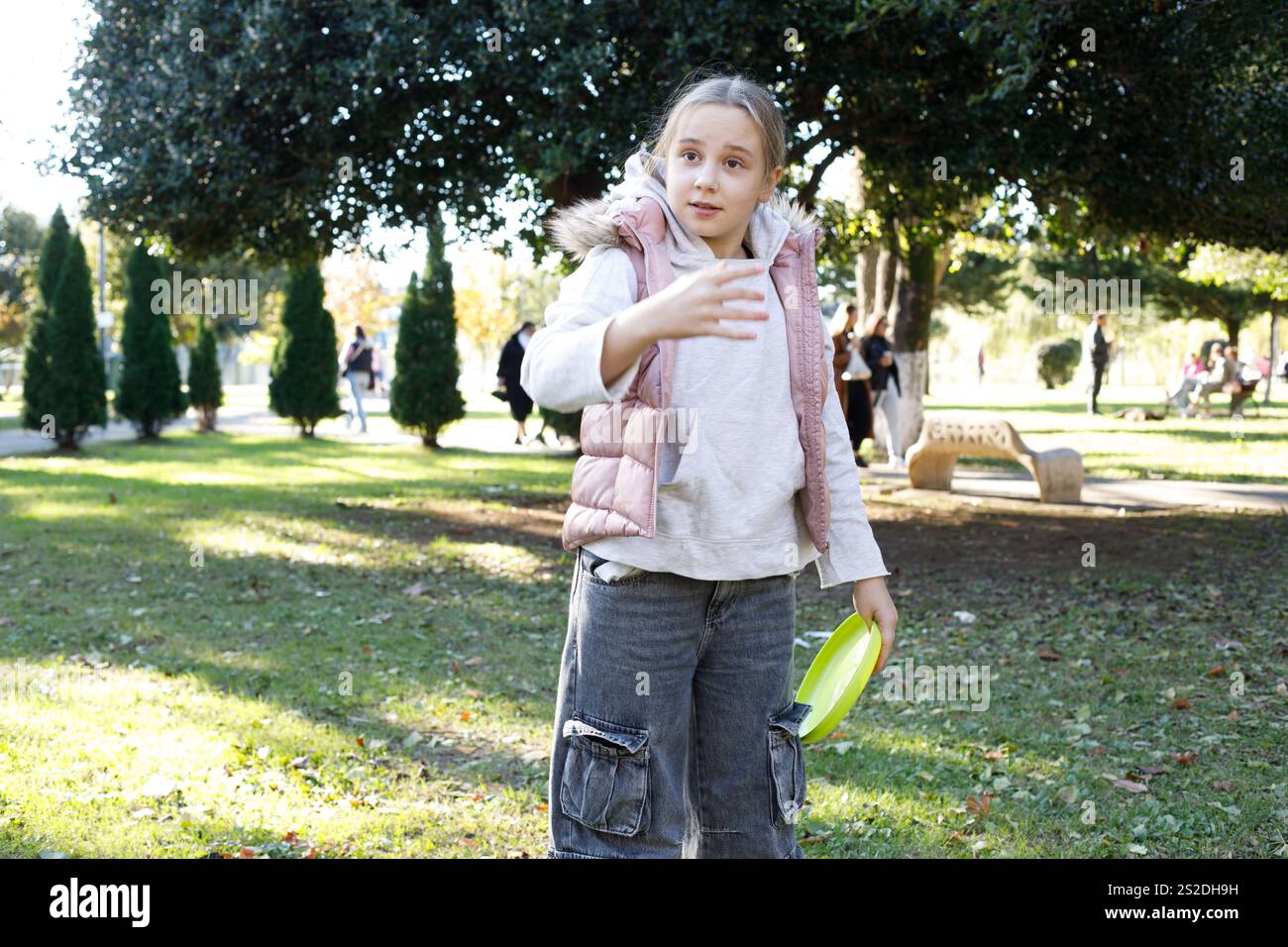 Positive happy girl child playing flying disc in a sunny, green outdoor ...
