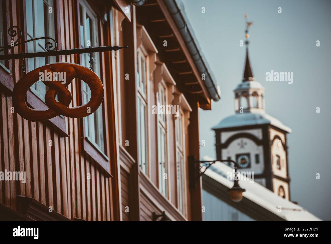 Pretzel signboard hanging in Røros, Norway, with the iconic clock tower ...
