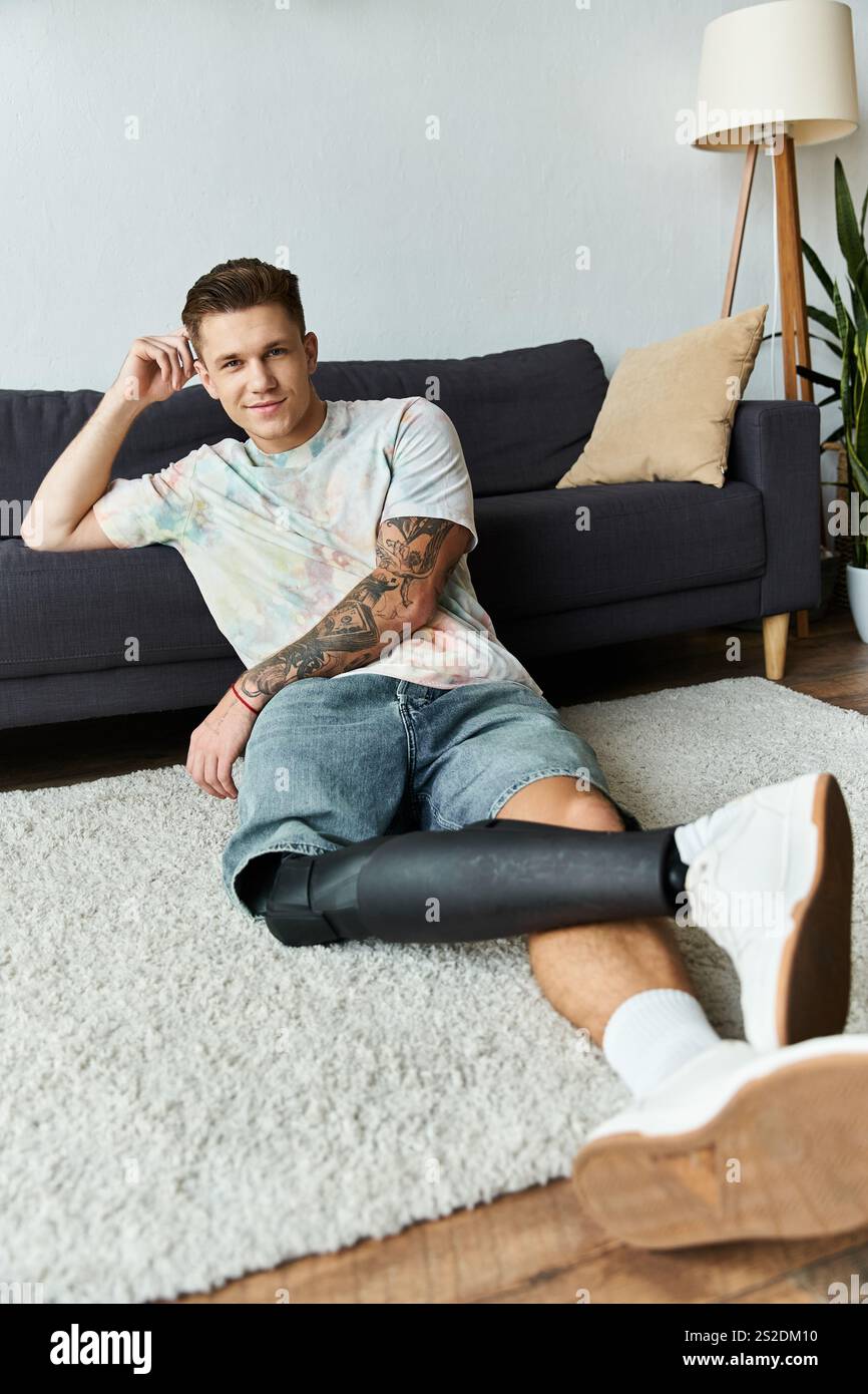 Handsome young man with tattoos sits casually on the floor, proudly ...