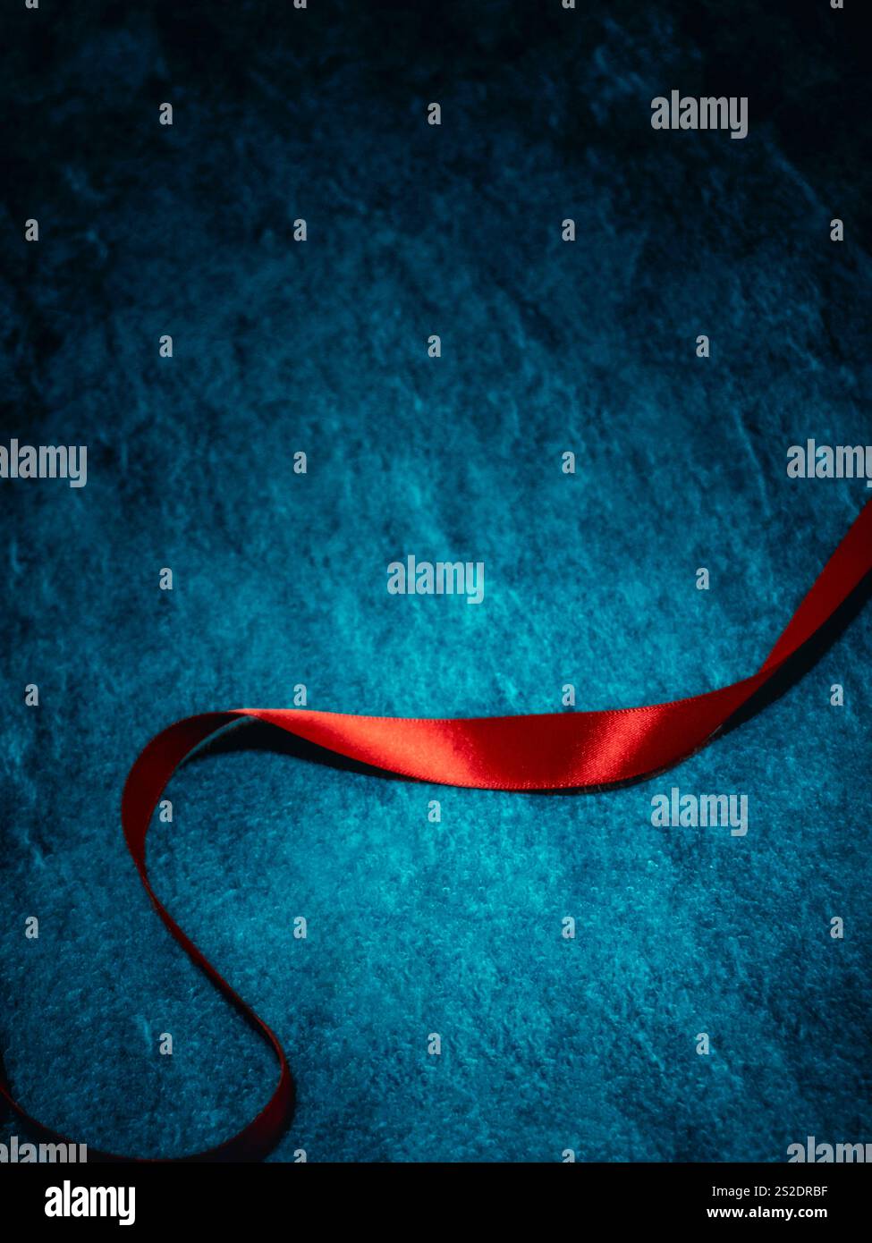 Red ribbon across textured blue background Stock Photo - Alamy