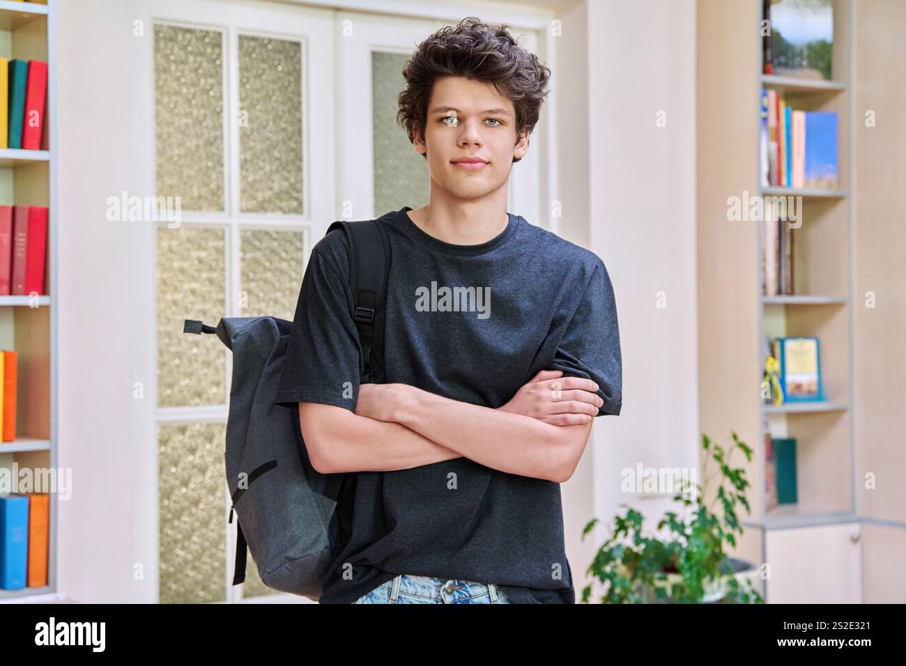 Portrait of college student guy with crossed arms inside educational ...
