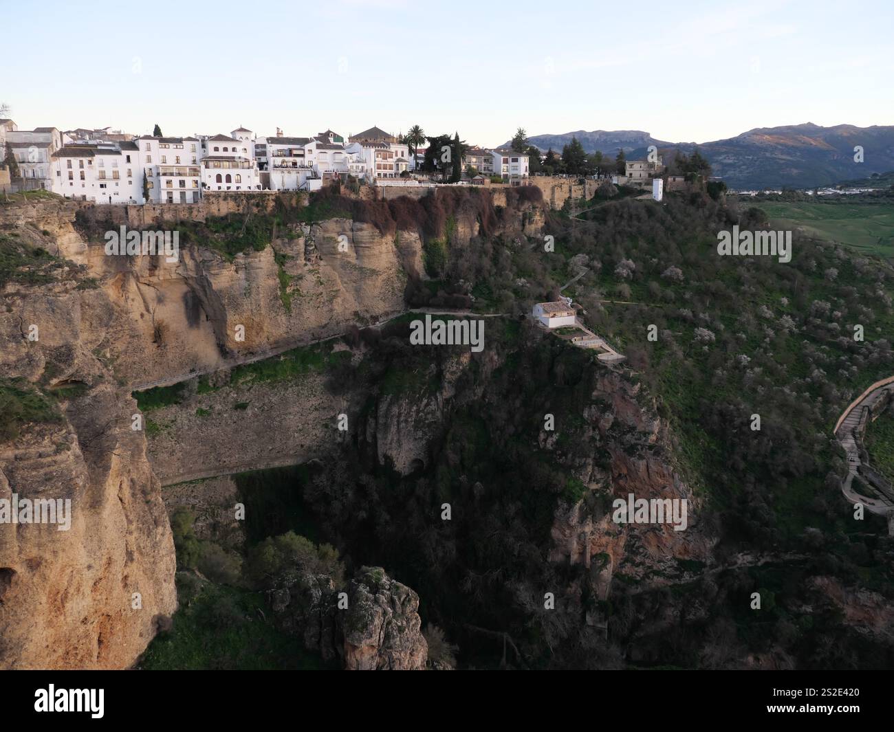 Houses stand spectacularly on the edge above a steep rock face next to ...