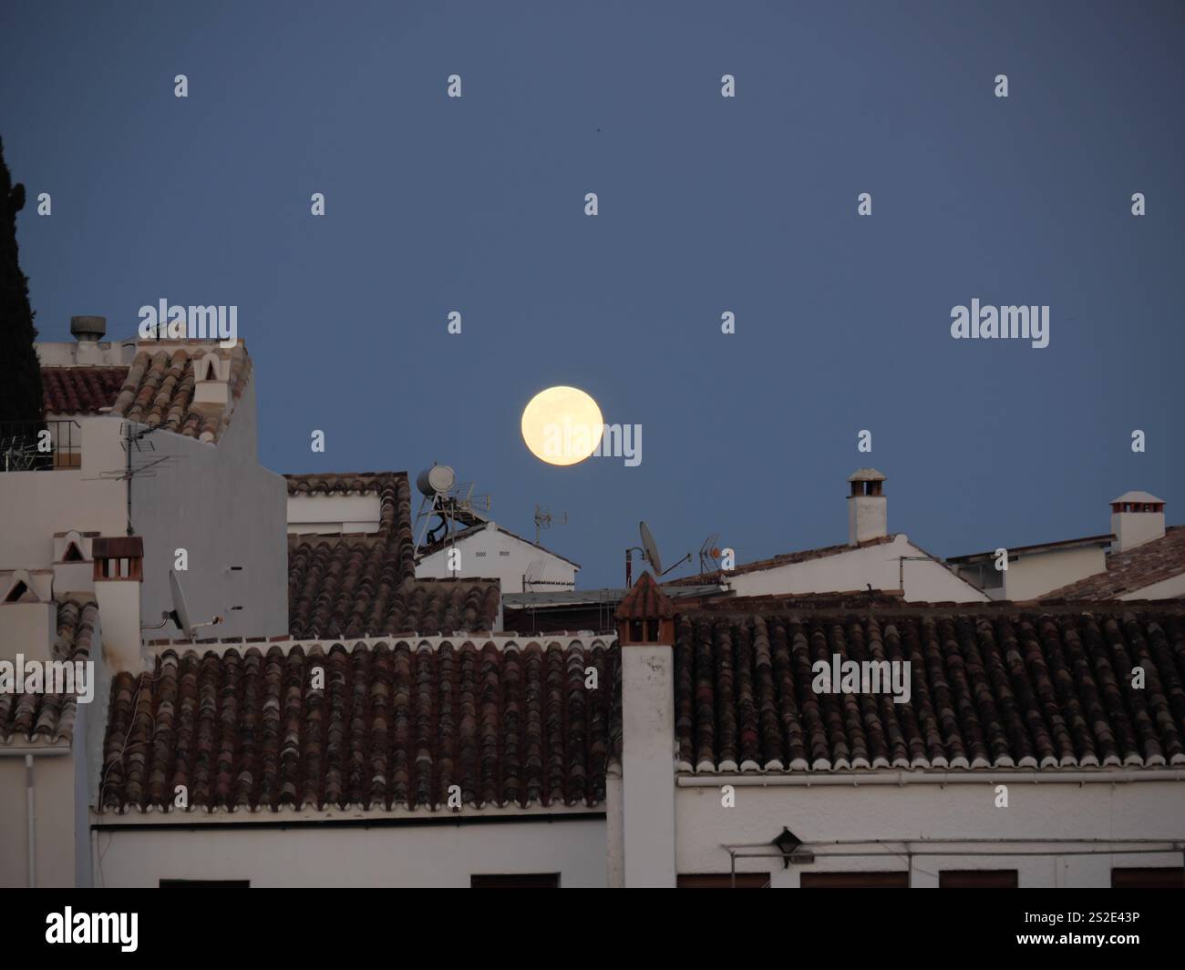 The rising full moon in the sky over Spanish houses in Ronda Spain ...
