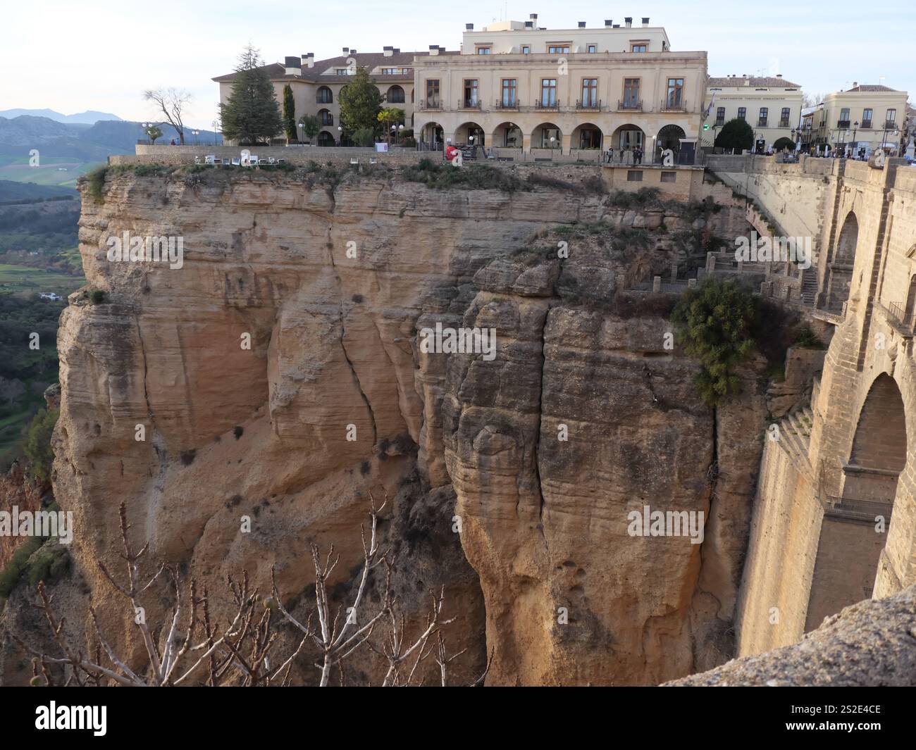Houses stand spectacularly on the edge above a steep rock face next to ...