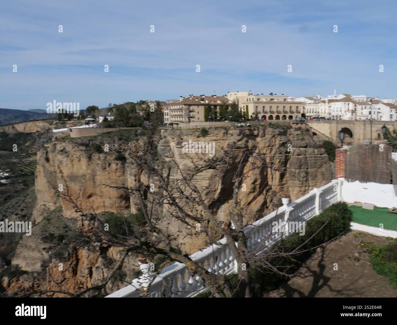 Houses stand spectacularly on the edge above a steep rock face next to ...