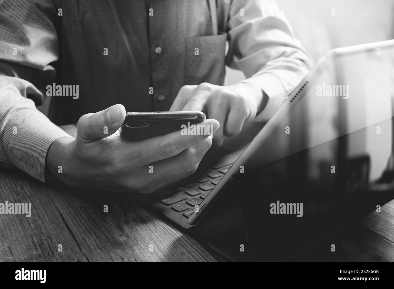 success businessman using smart phone,digital tablet docking smart keyboard,on wooden desk,black ...