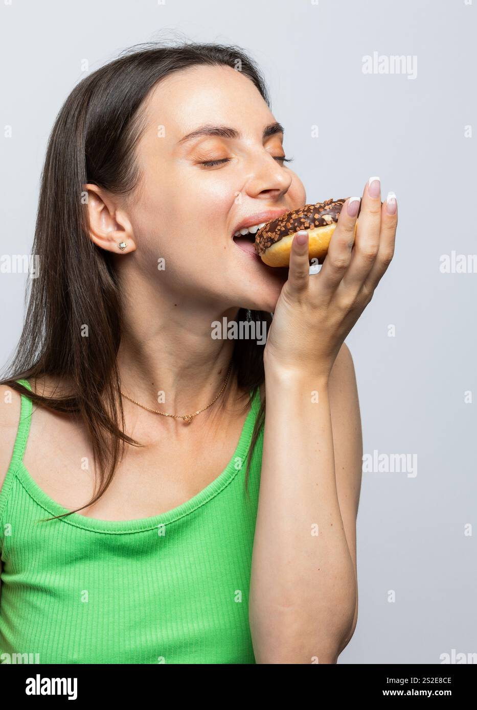 Happy woman biting into a delicious donut and enjoying it so much. On ...
