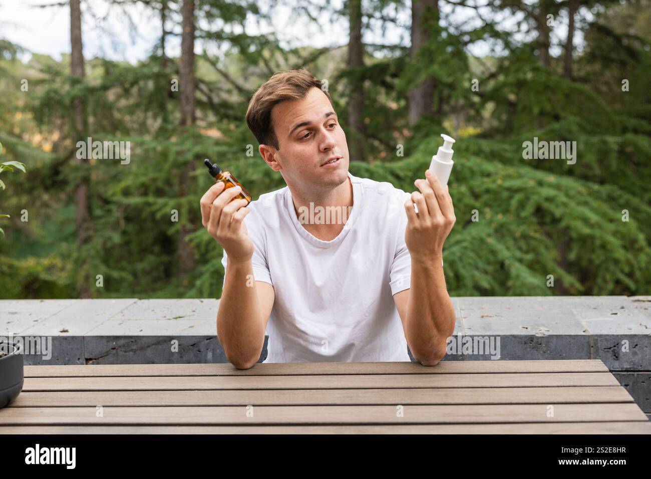 Man choosing between two cosmetic products for his skincare routine ...