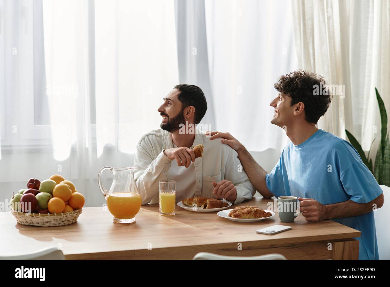 Two gay men share a joyful breakfast at their stylish apartment ...