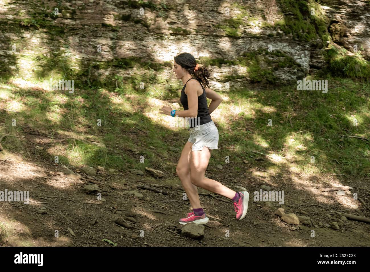 Woman running on a forest trail surrounded by natural greenery and ...
