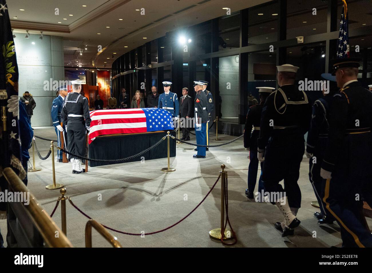 Mourners view the changing of guard of the joint services military honor guard as the casket of ...