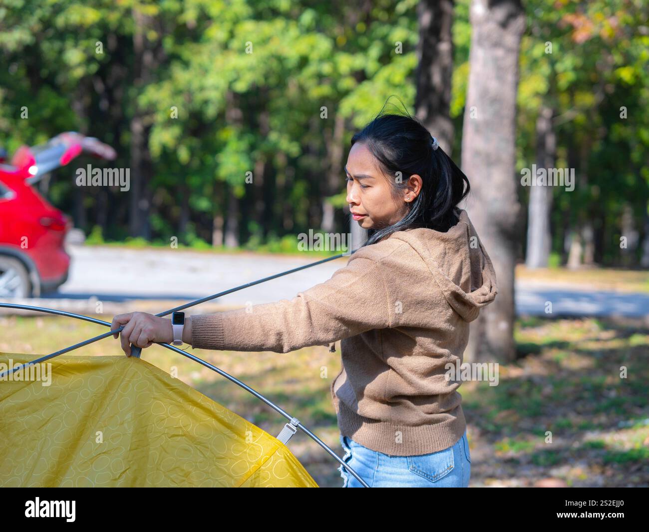 Mother and daughter are helping each other set up a tent in nature on a ...