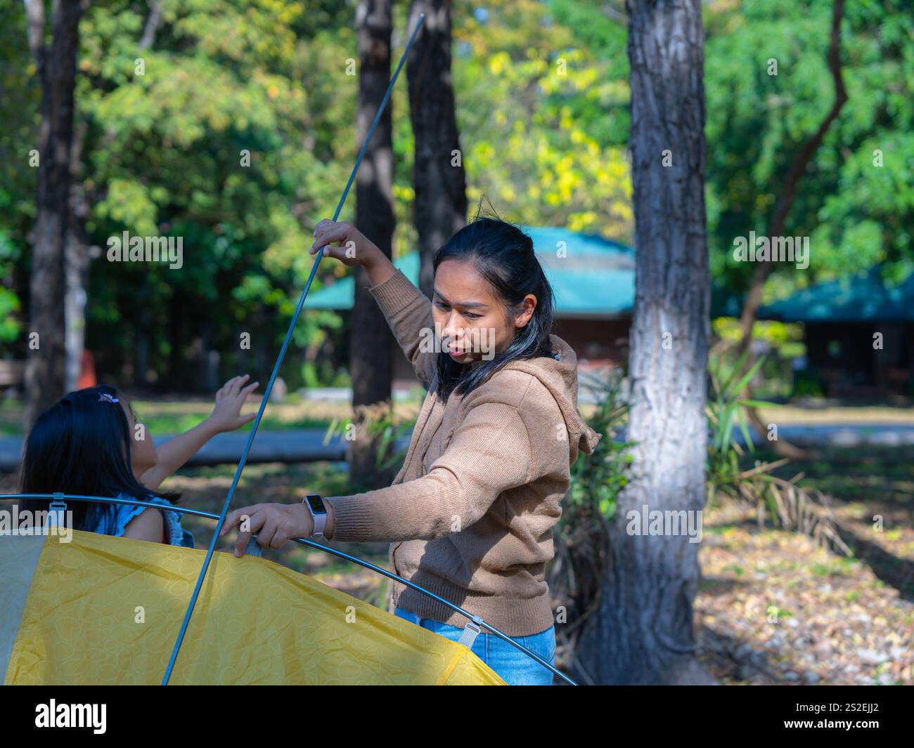 Mother and daughter are helping each other set up a tent in nature on a ...