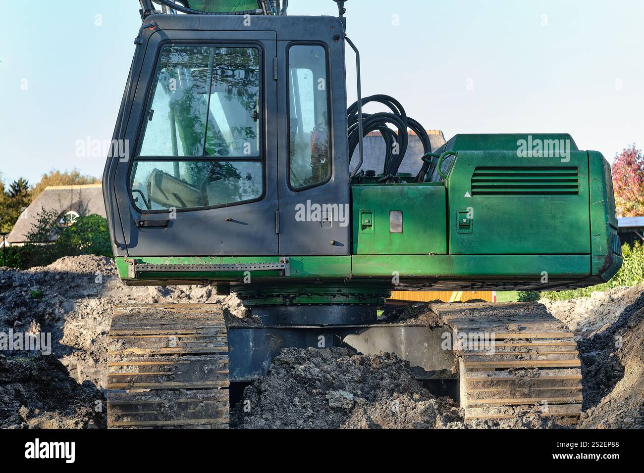 Side view on an green excavator operates at a construction site where a ...