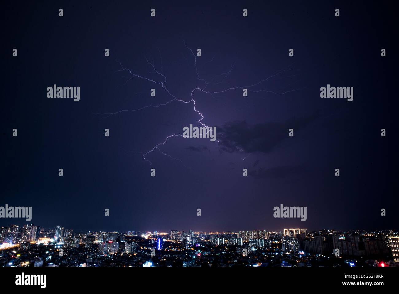 A city skyline with a lightning bolt in the sky. The sky is dark and ...
