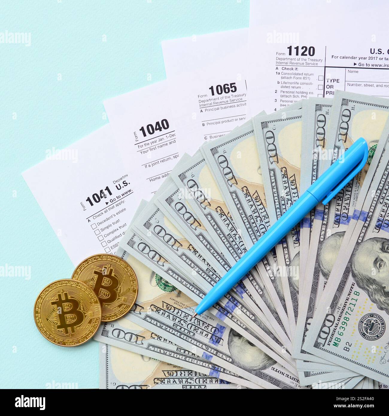 Bitcoins lies with the tax forms and hundred dollar bills on a light ...