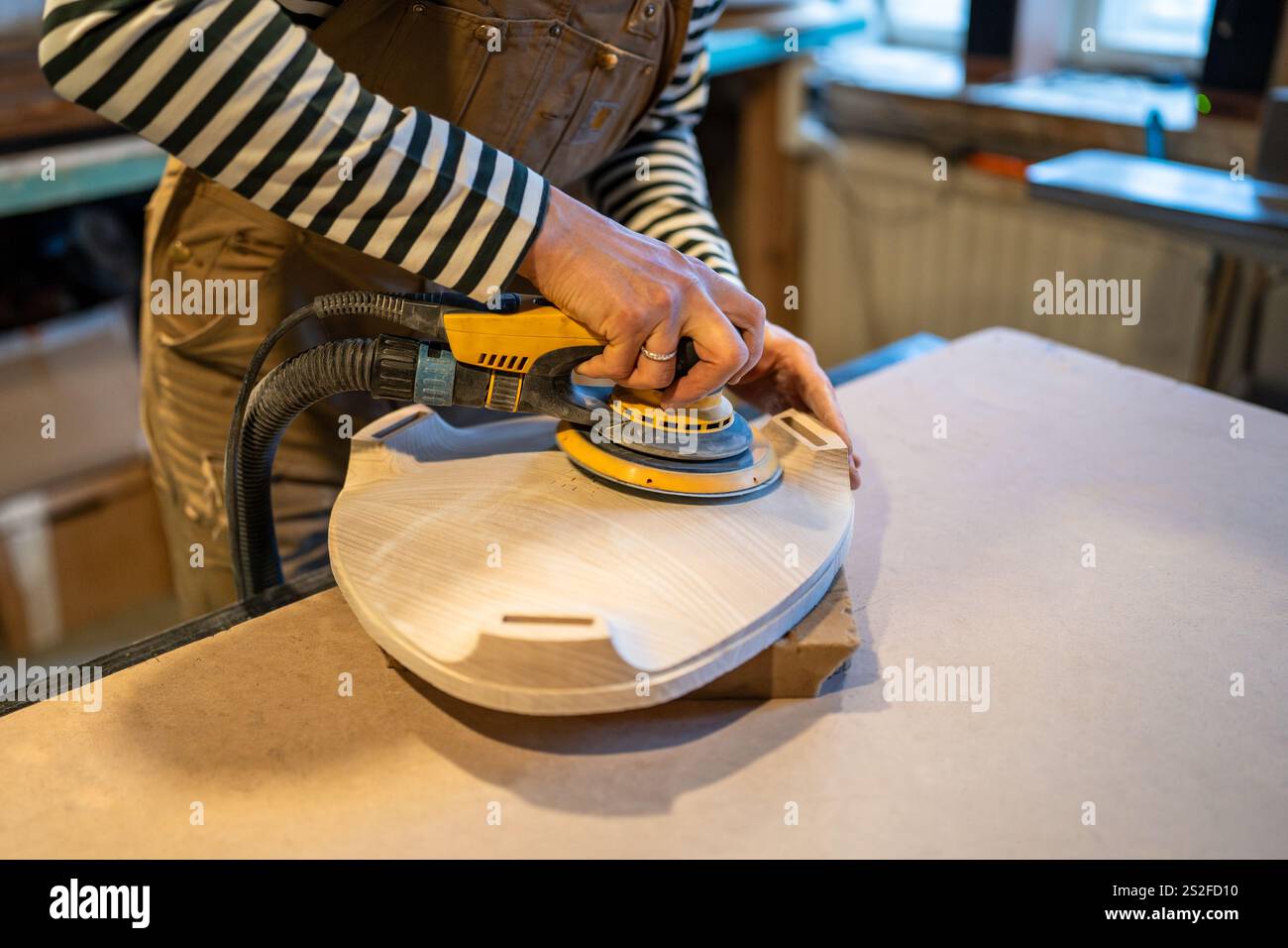 Closeup of sanding wood with orbital sander at workshop. Carpentry ...