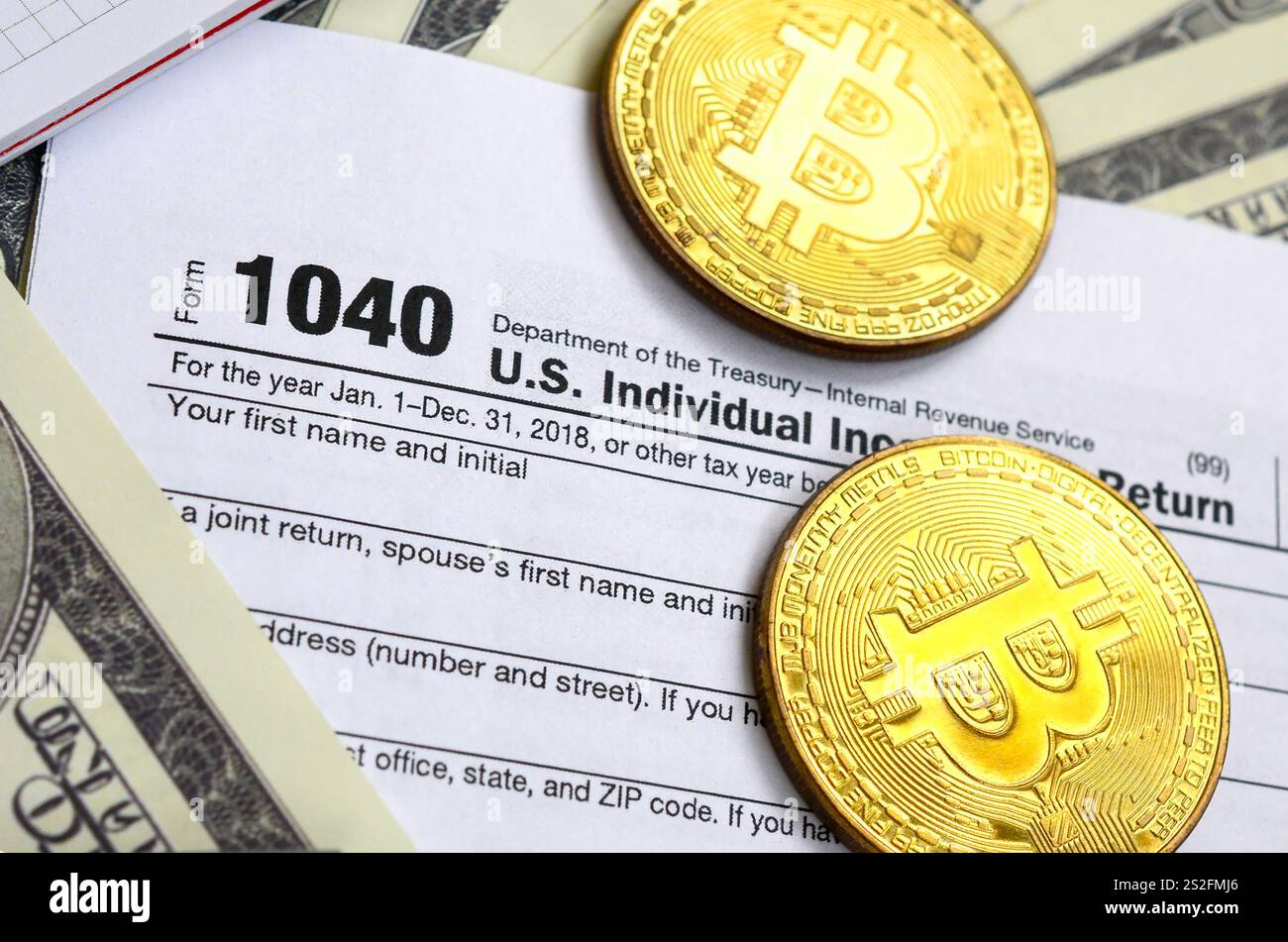 The pen, bitcoins and dollar bills is lies on the tax form 1040 U.S ...