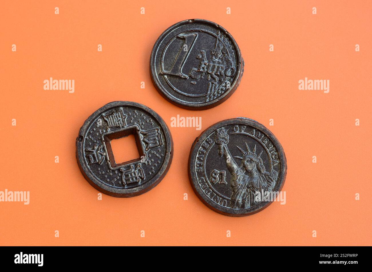 Three chocolate products in the form of Euro, USA and Japan coins lie ...