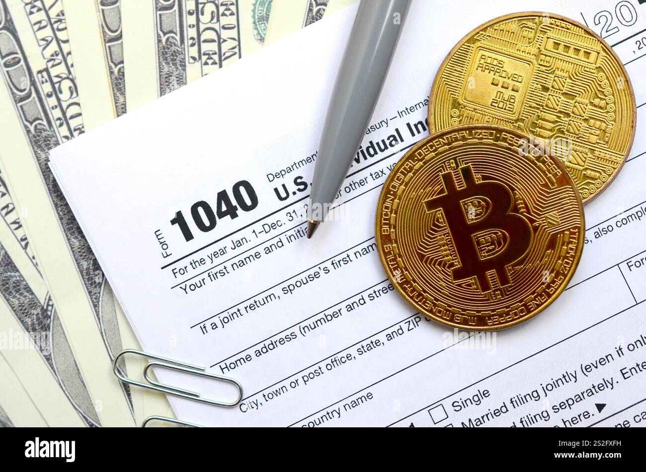The pen, bitcoins and dollar bills is lies on the tax form 1040 U.S ...